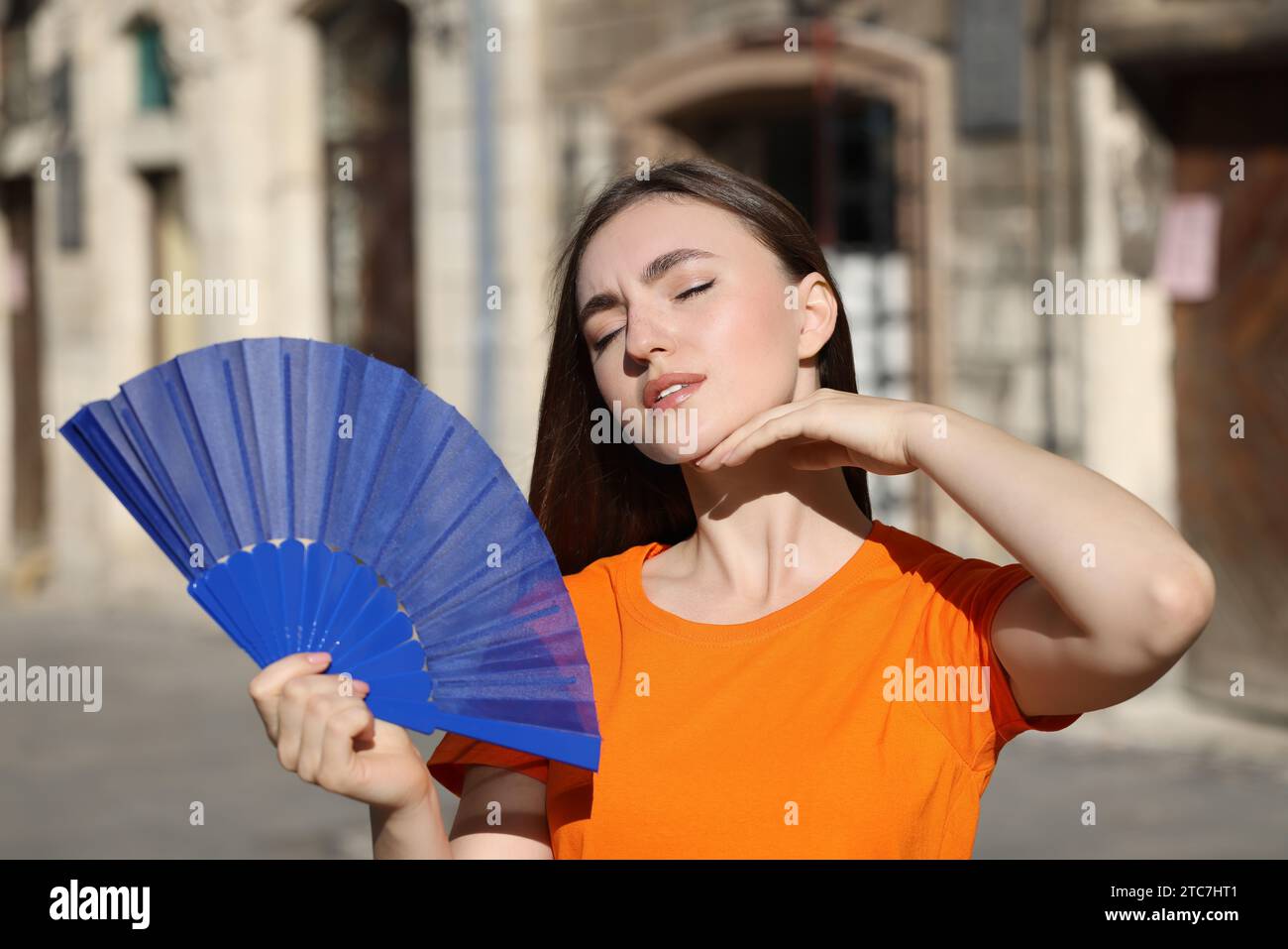 Woman with hand fan suffering from heat outdoors Stock Photo - Alamy