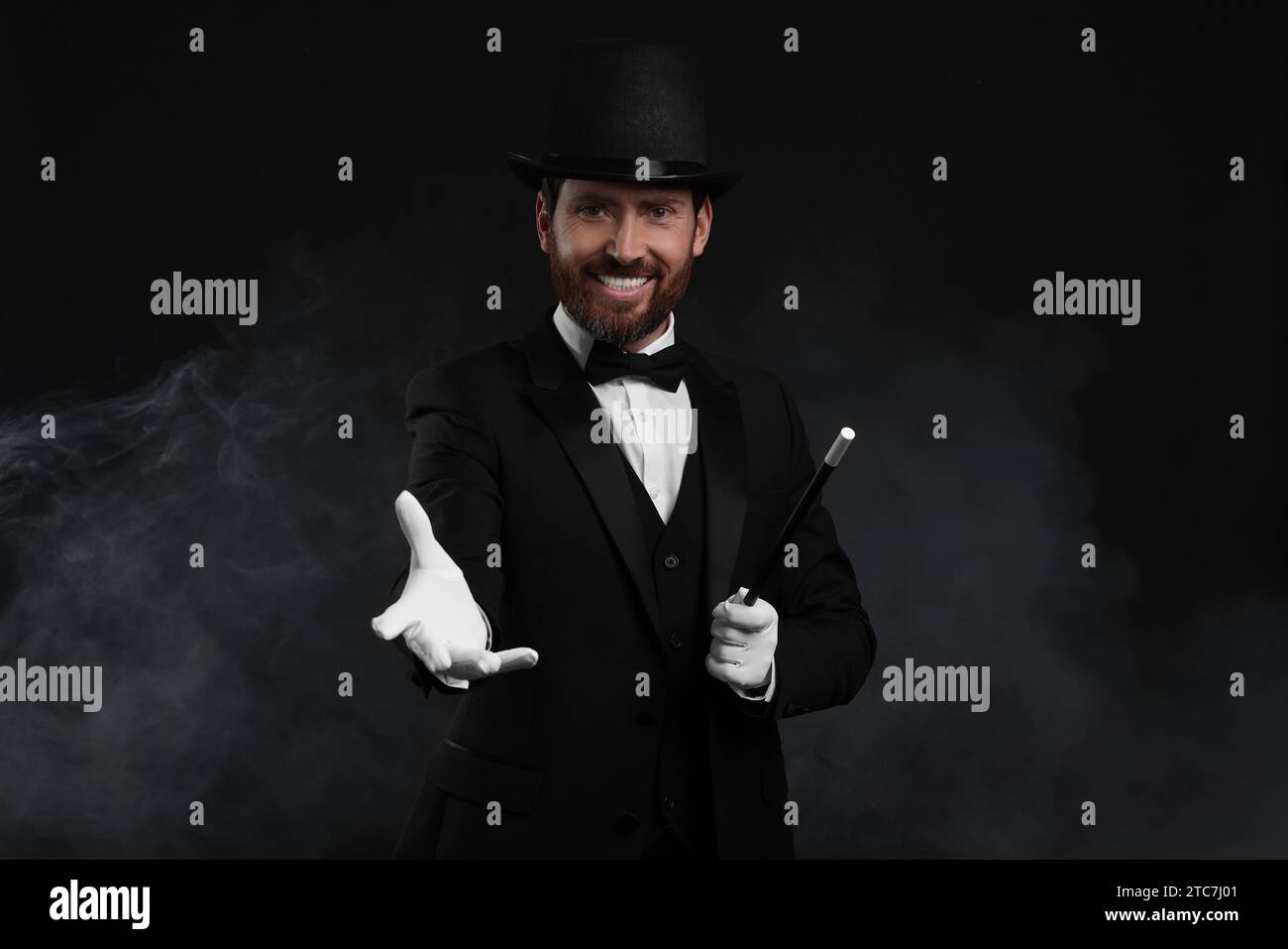 Happy magician holding wand in smoke on black background Stock Photo ...
