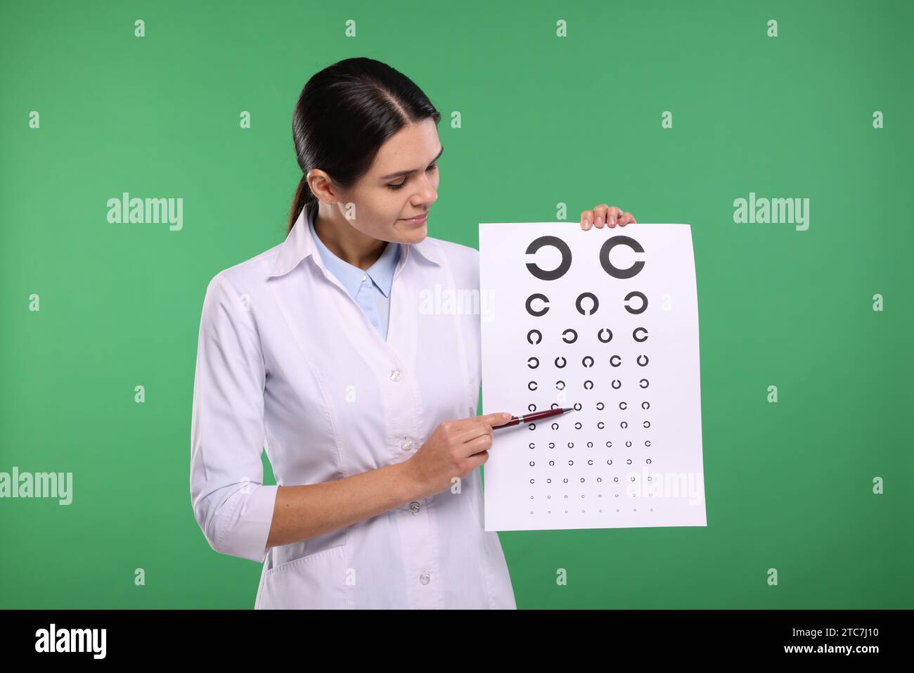 Ophthalmologist pointing at vision test chart on green background Stock ...