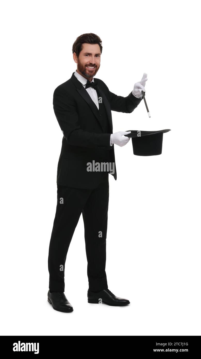 Happy magician showing magic trick with top hat on white background ...