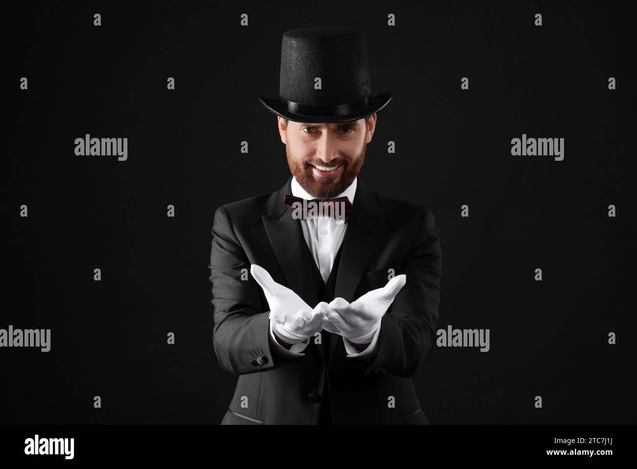 Happy magician in top hat on black background Stock Photo - Alamy