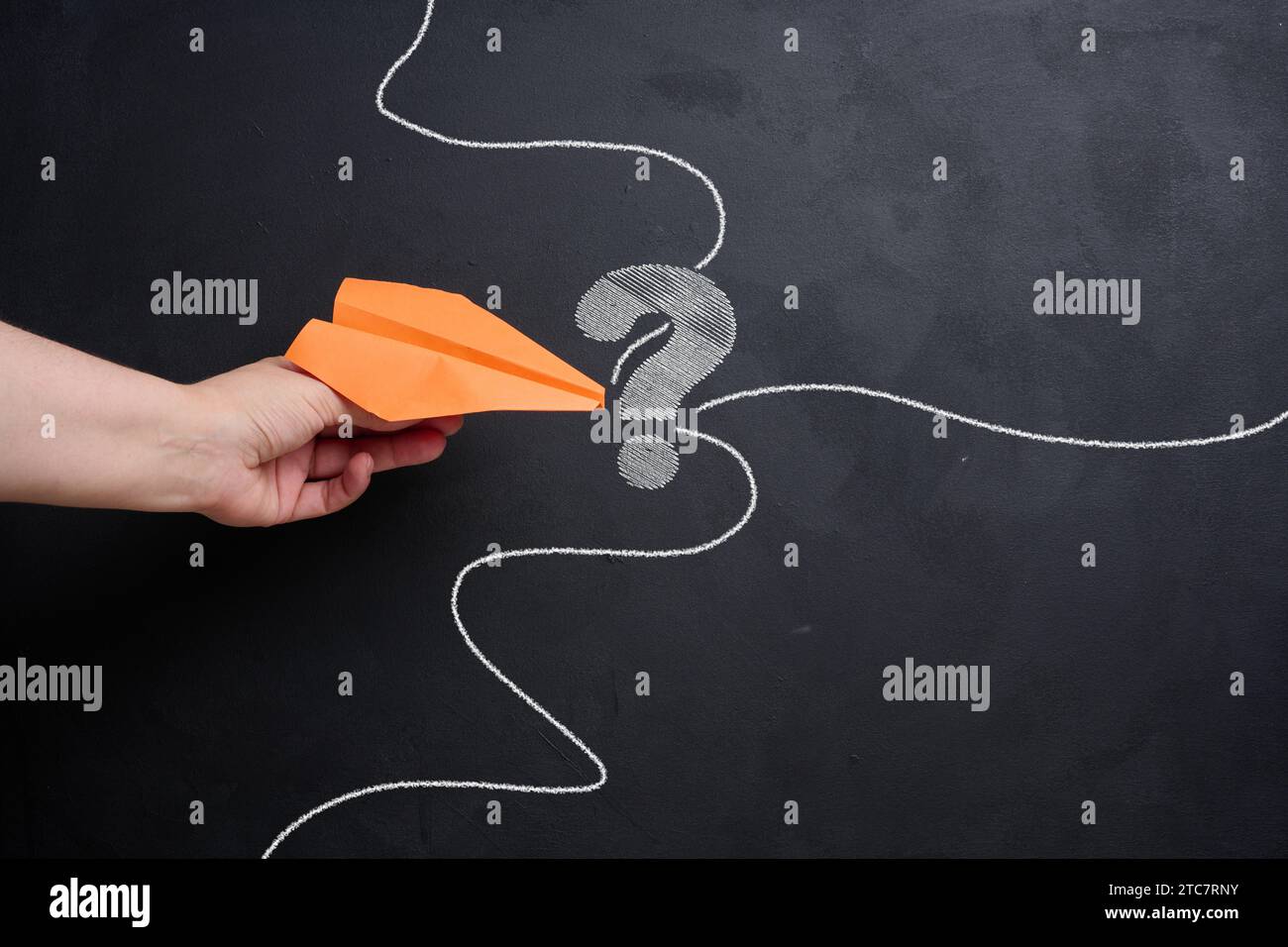 A hand holds a paper airplane with various trajectories marked by ...