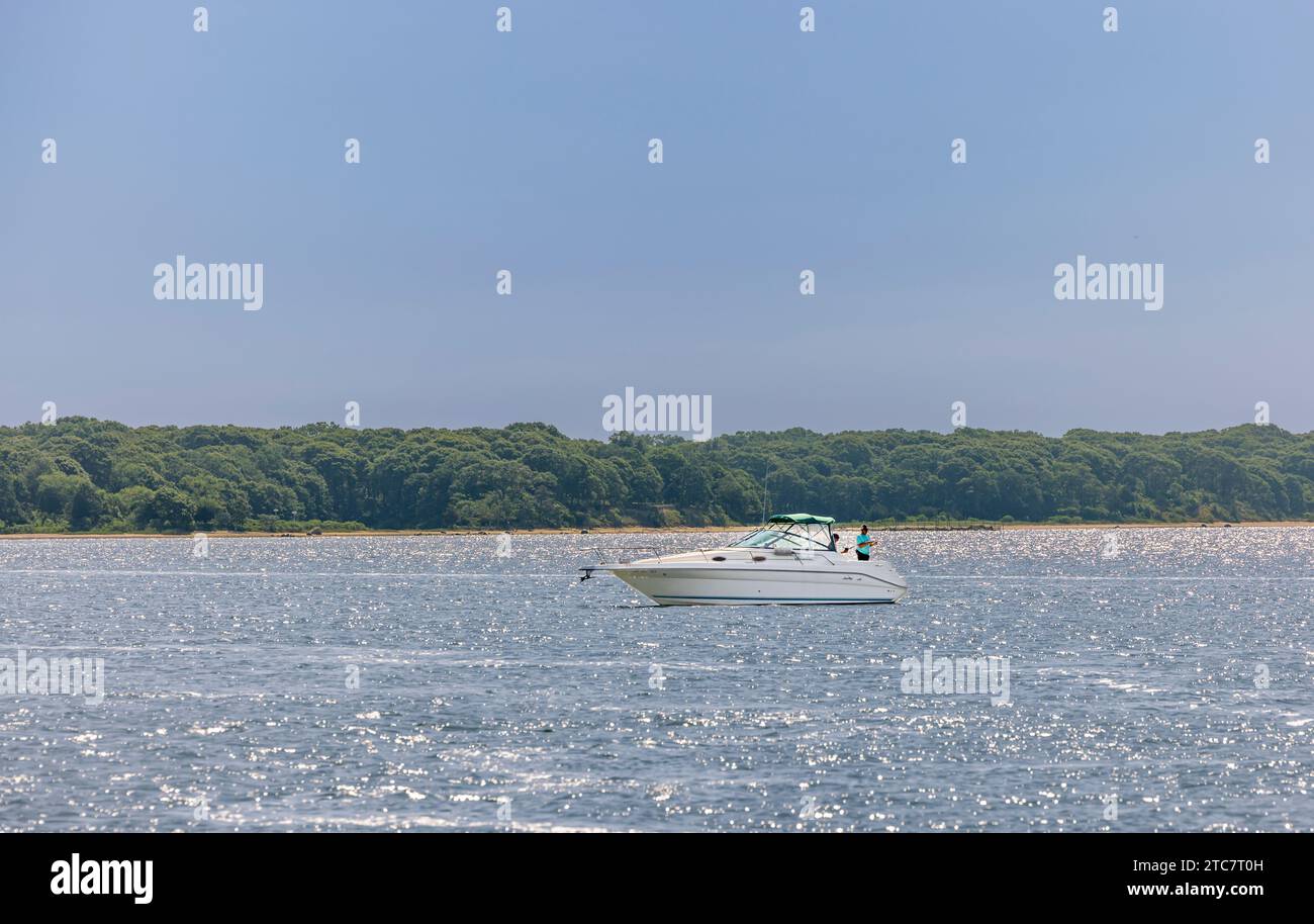 two people fishing off the back of a boat with shelteri island in the ...