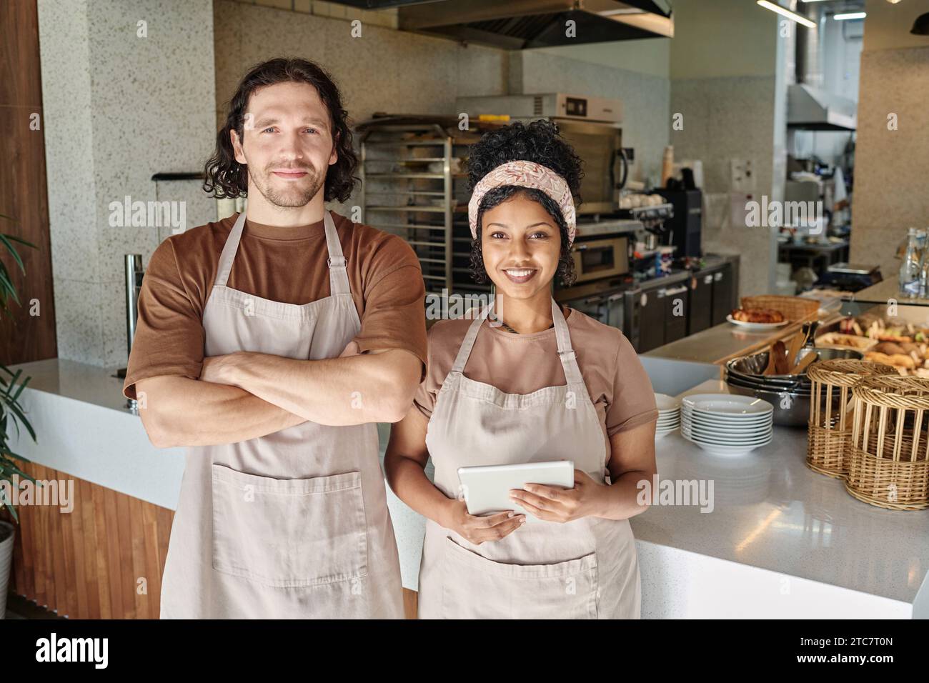Caucasian and african american waiters working at cafe posing nearby ...