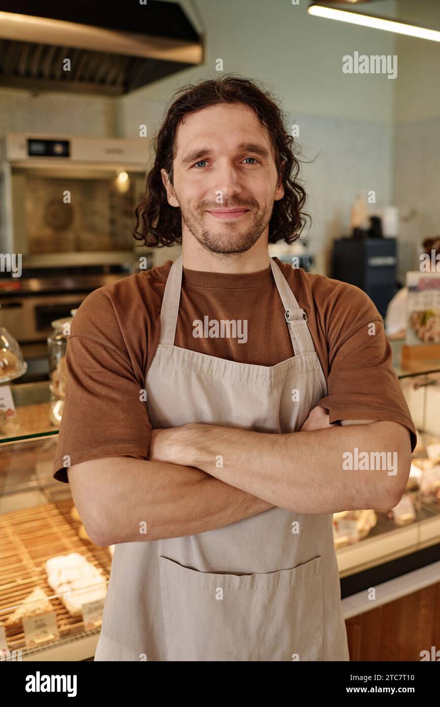 Bakery worker confidently standing against counter with arms crossed ...