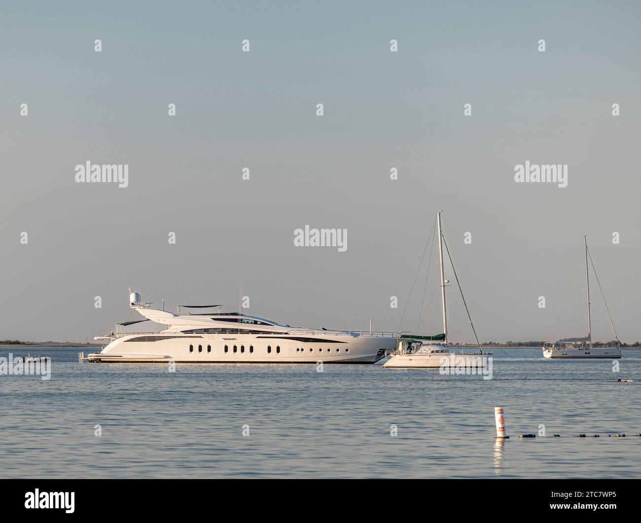 Large motor yacht and two sail boats at anchor Stock Photo - Alamy