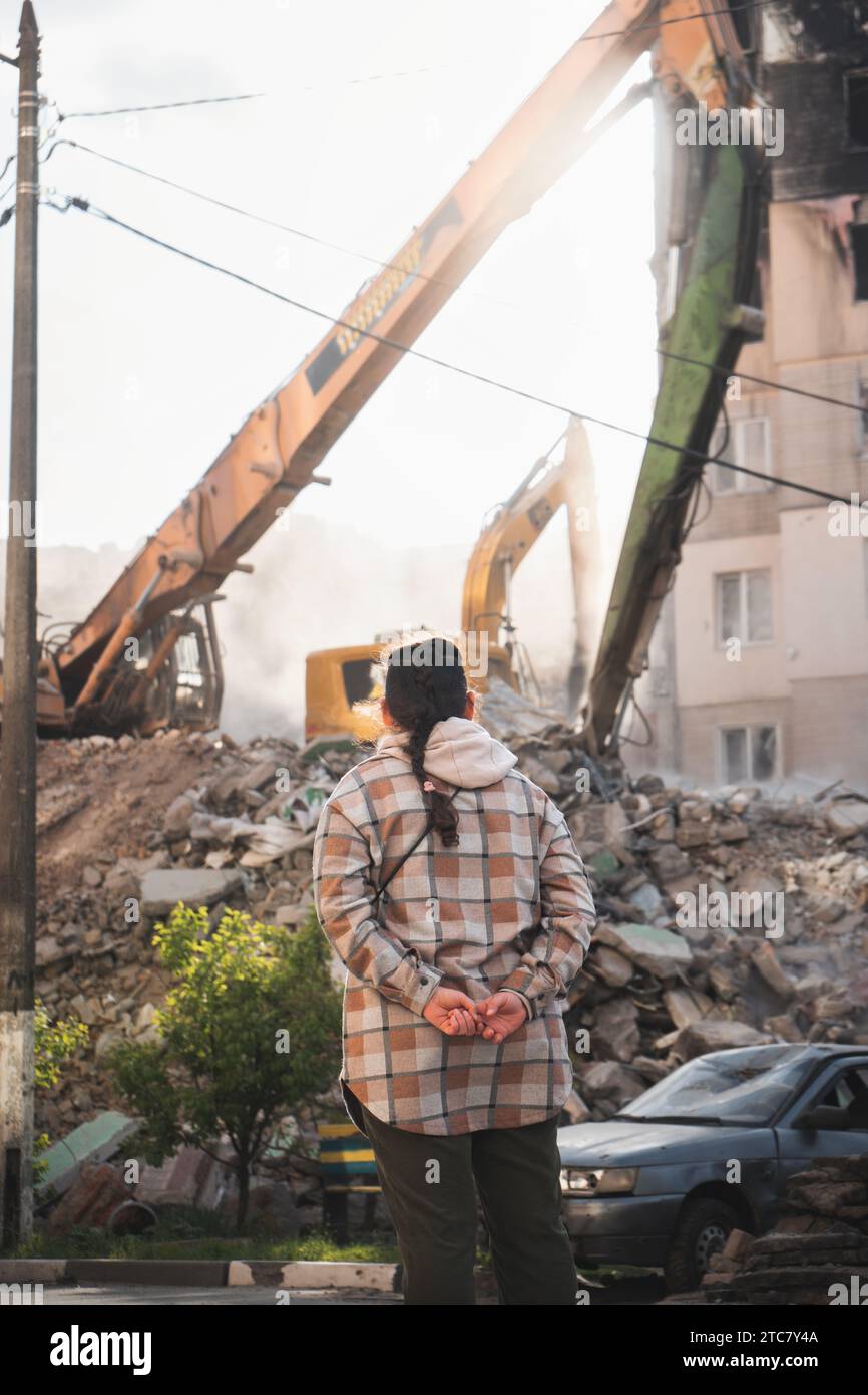 Girl looking at the demolition process of residential building ...