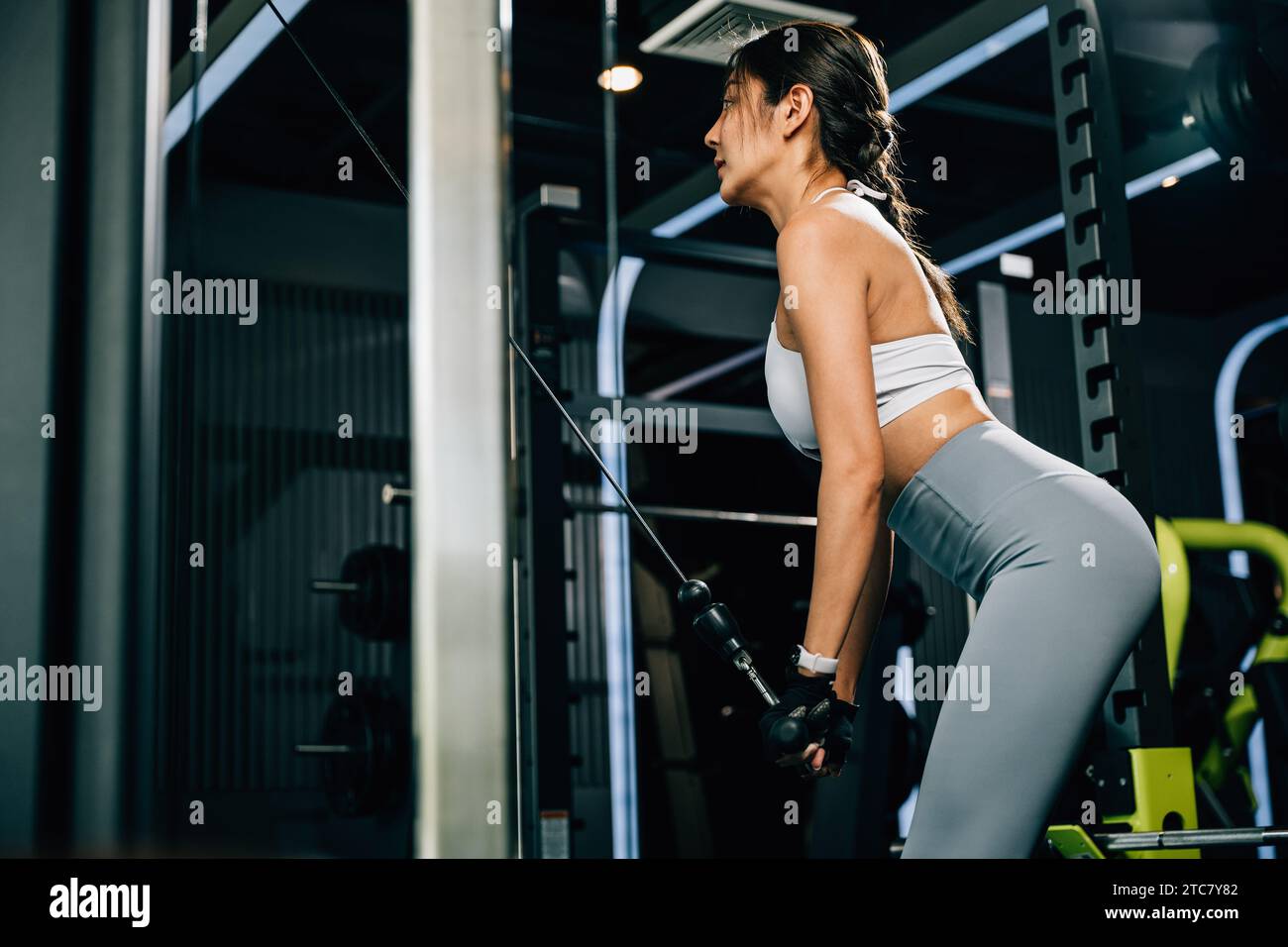 Slim and strong young woman working out on a pull-down weight machine ...