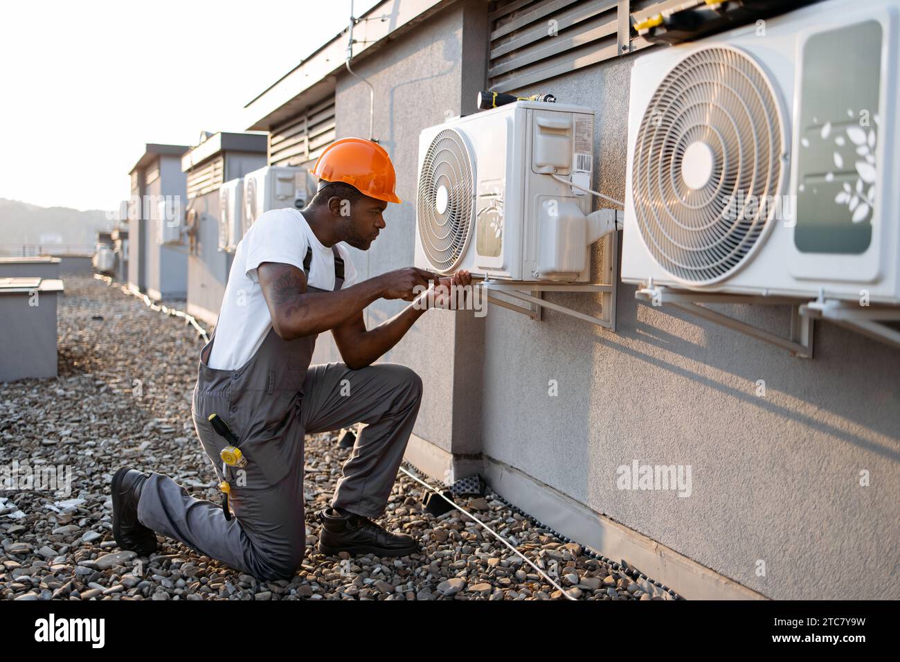 Male builder repairing conditioner with screwdriver on roof Stock Photo ...