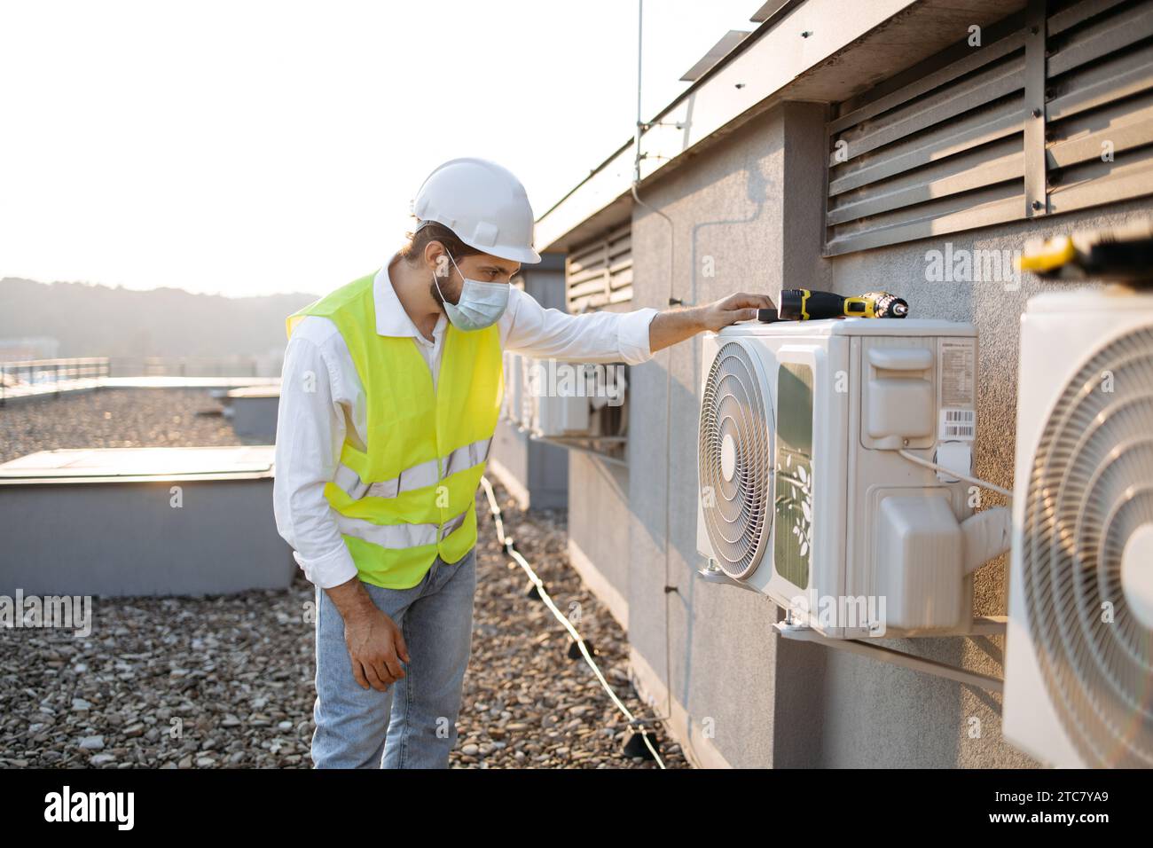 Craftsman in face mask cleaning air conditioner on rooftop Stock Photo ...