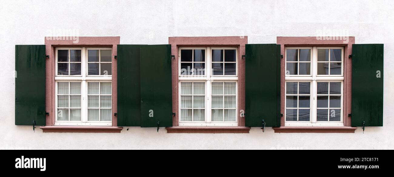 Three windows in a row with dark metal shutters on white wall Stock ...