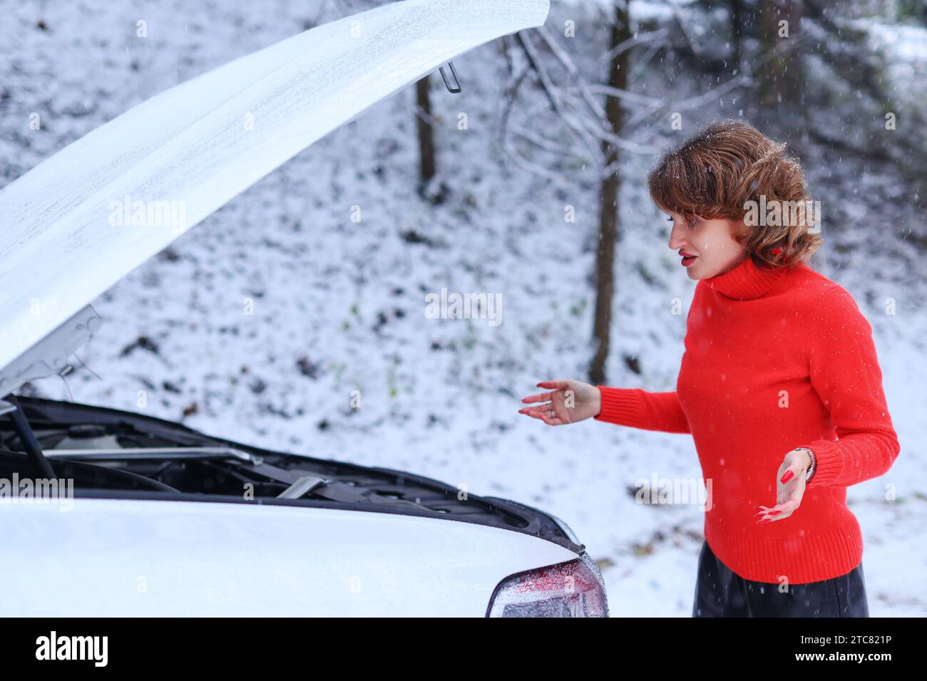 a girl stands in shock by the open hood of a broken car Stock Photo - Alamy