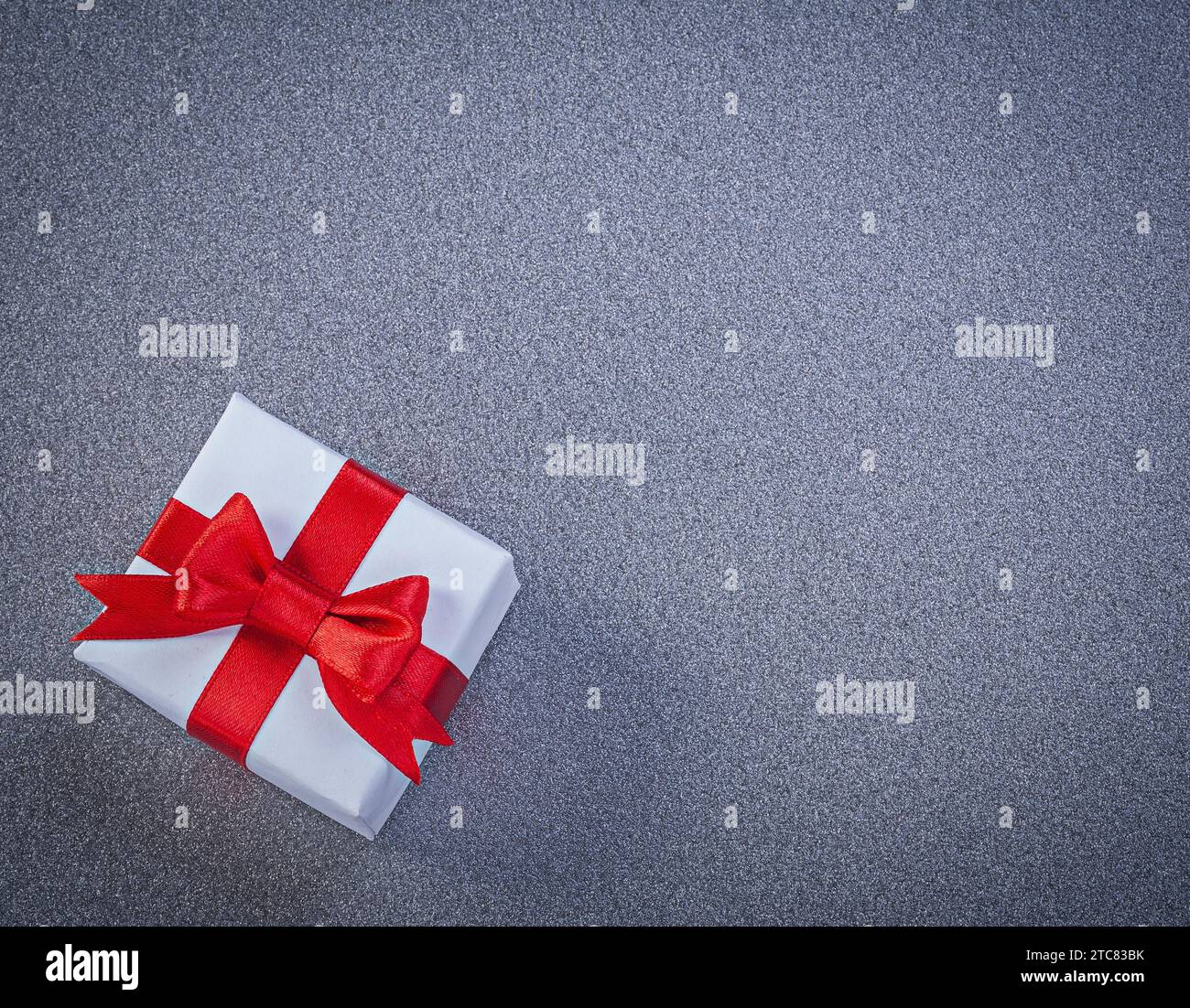 White boxed present with red tied bow on grey surface holidays concept ...