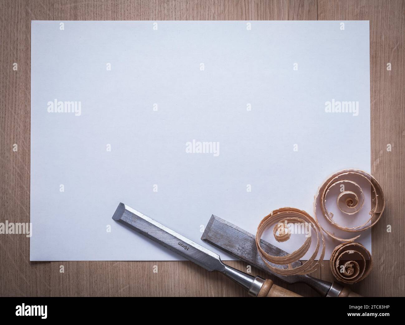 Wooden shavings flat chisels and clean sheet of paper on wood board ...