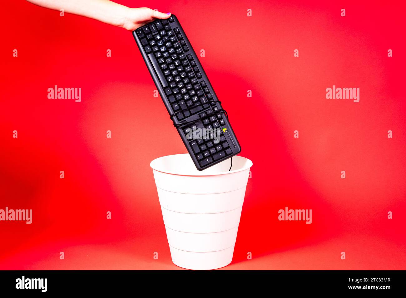 Woman putting a computer keyboard in the e-waste trash bin, recycling ...