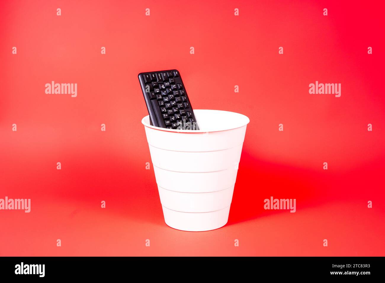 Woman putting a computer keyboard in the e-waste trash bin, recycling ...
