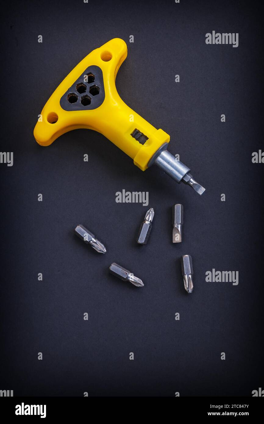 Yellow screwdriver with little bits on black background Stock Photo - Alamy