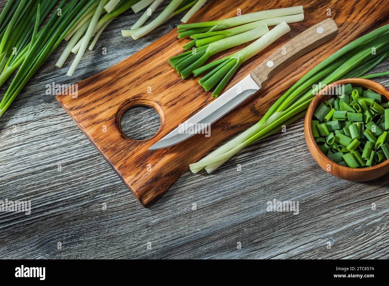 Chopped green spring scallions kitchen knife wooden cutting board ...