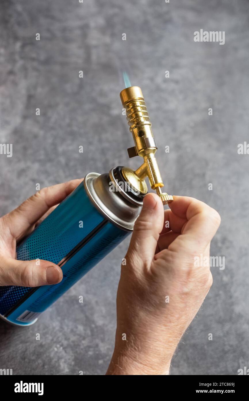 man's hand regulates the flame on a lit gas burner for ignition Stock ...