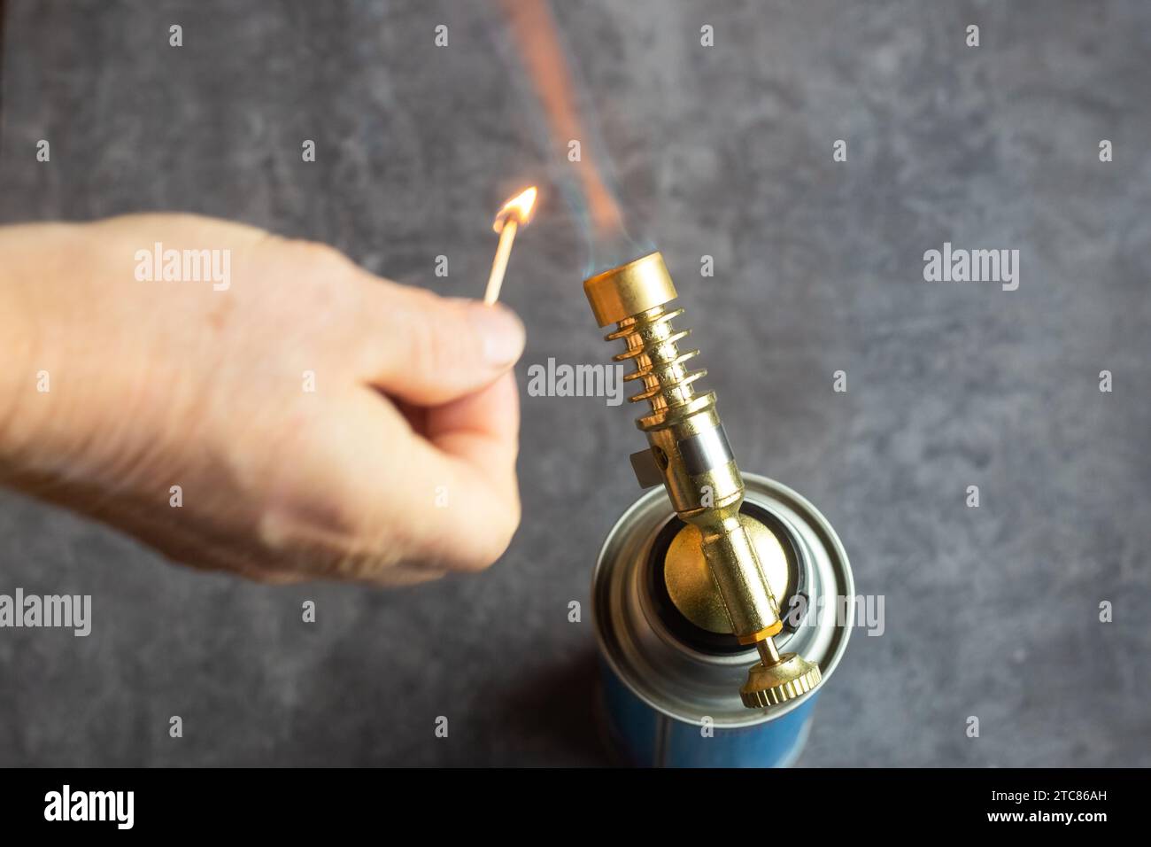 a gas cylinder with a gas burner burns with a flame lit by a man with a ...