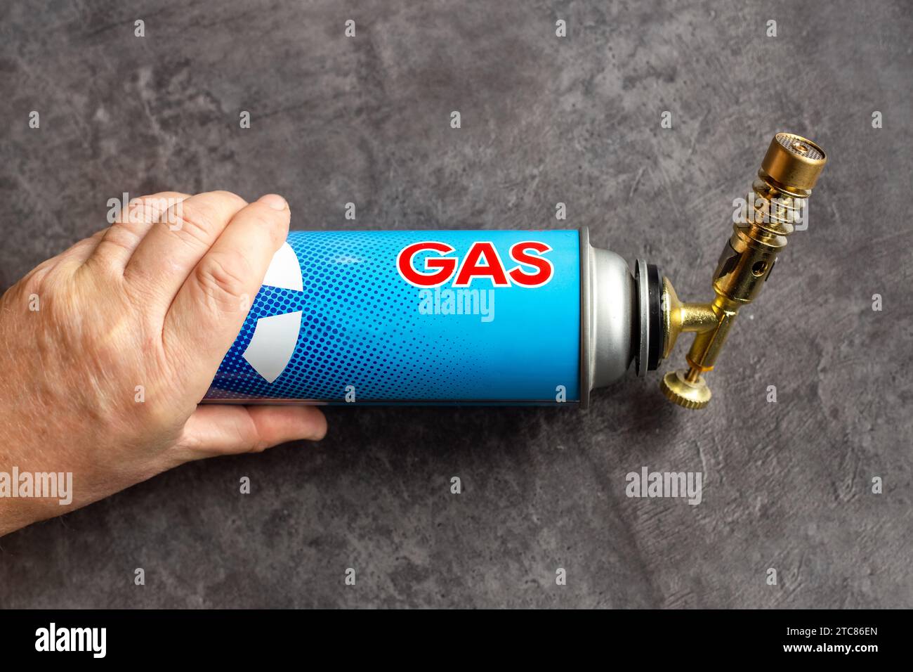 gas cylinder with a gas burner attached for ignition, held by a man's ...