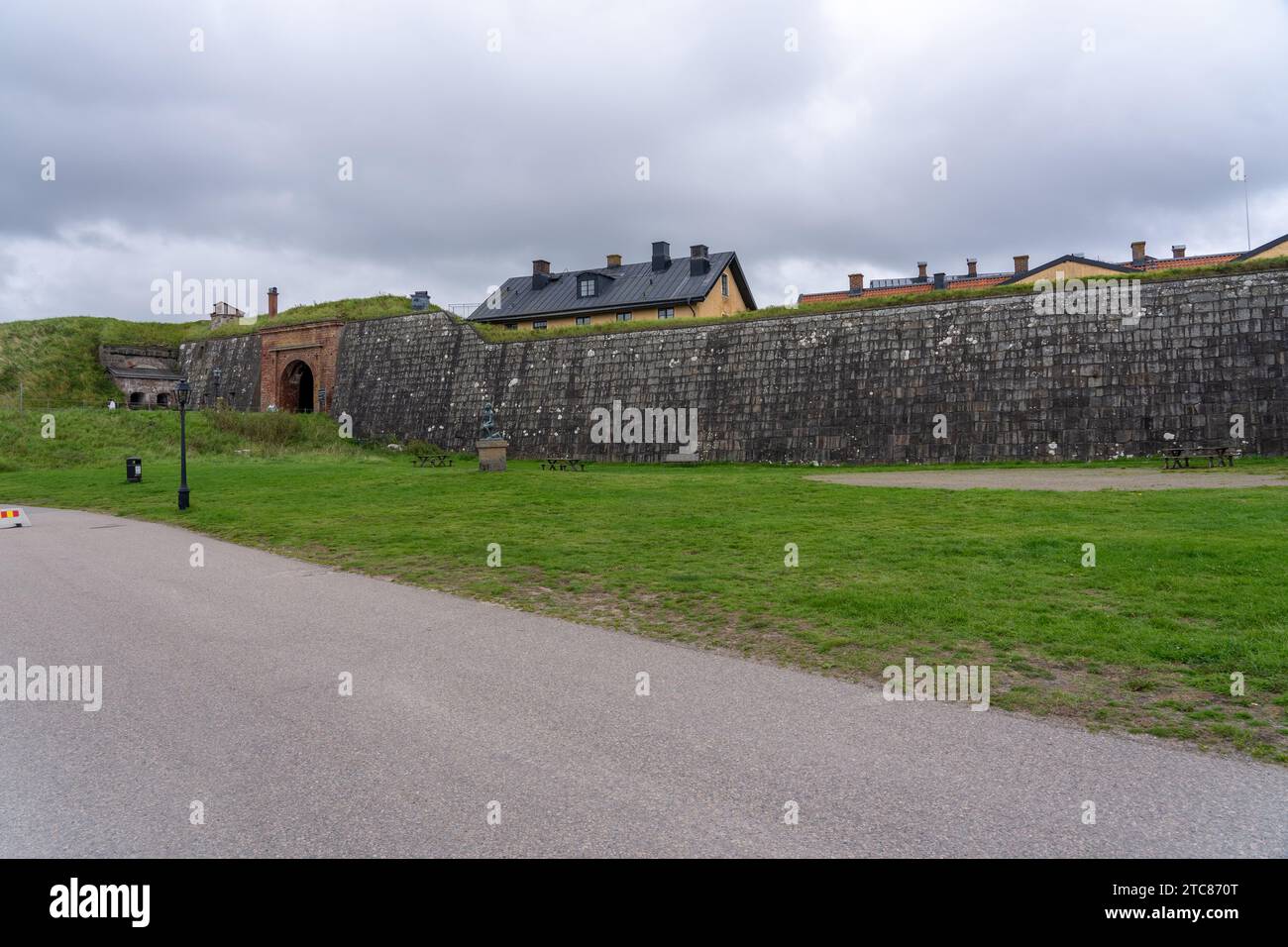A countryside road with a brick wall running alongside it, set amongst ...