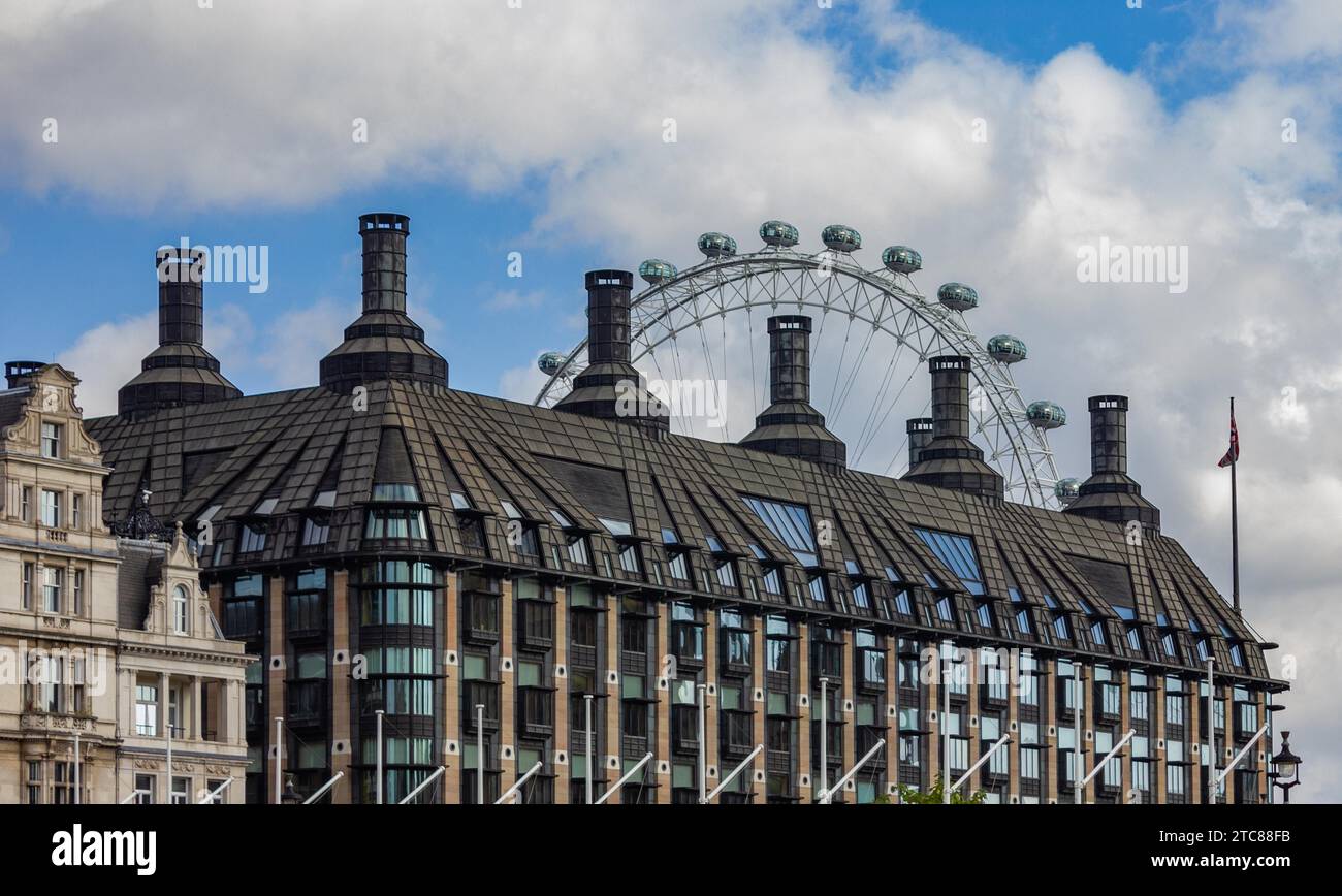 A picture of the London Eye peeking above some buildings on the other ...
