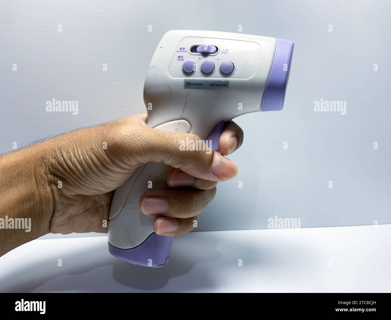 Hand holding temperature checker during Covid on white background Stock ...
