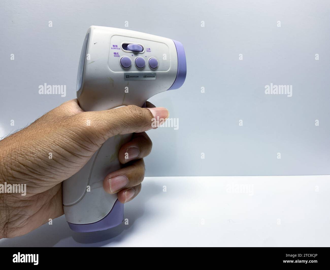 Hand holding temperature checker during Covid on white background Stock Photo - Alamy