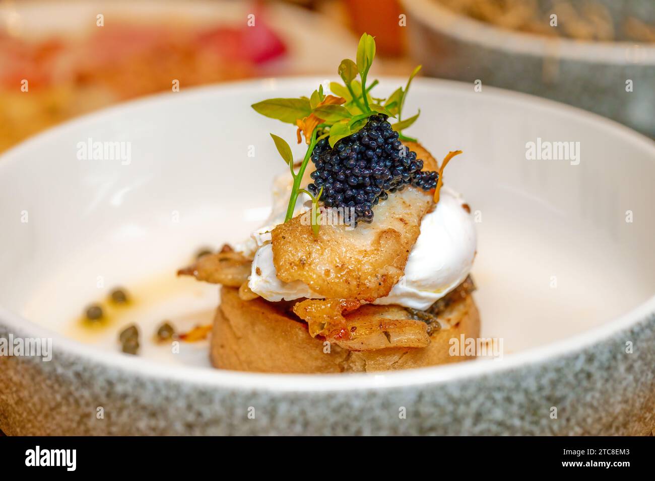 Gourmet appetizer with caviar and poached egg on toasted bread. Fine ...