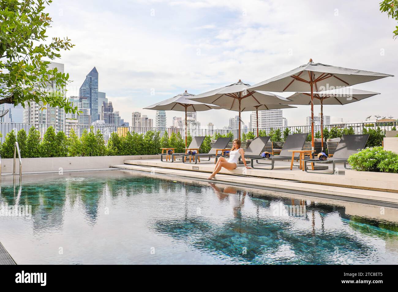Woman relaxing by pool in luxurious urban rooftop setting. Urban ...