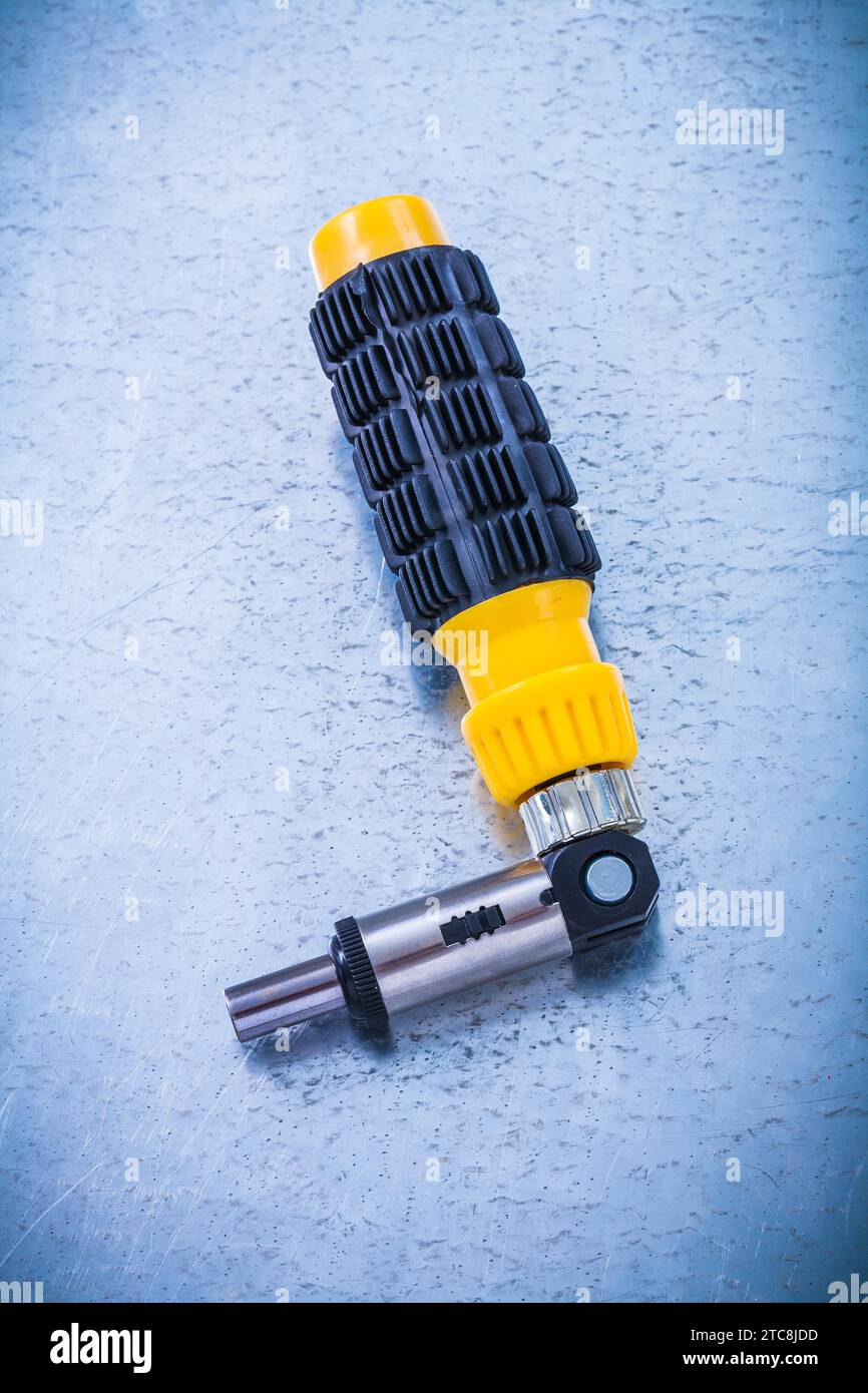 Reversible screwdriver with rubber handle on metallic background ...