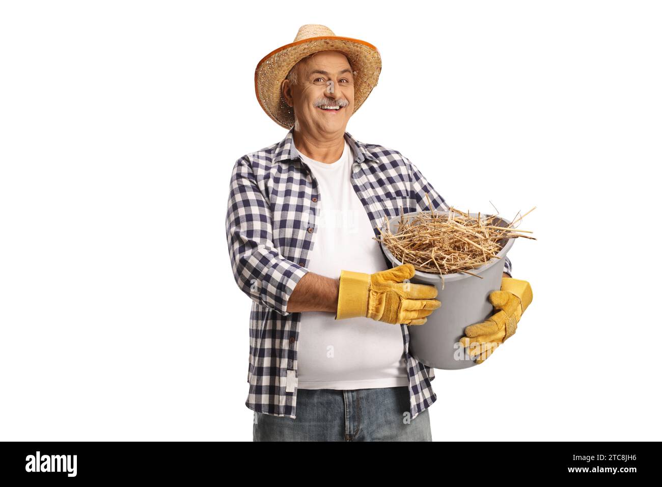 Happy mature farmer holding a bucket full of hay isolated on white ...