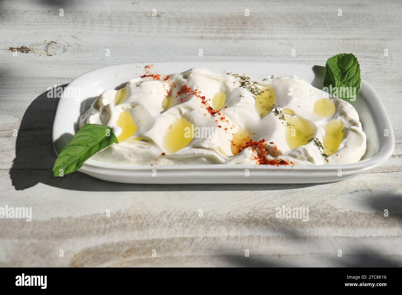 A Labneh platter garnished with herbs, hot pepper sprinkles, and mint ...