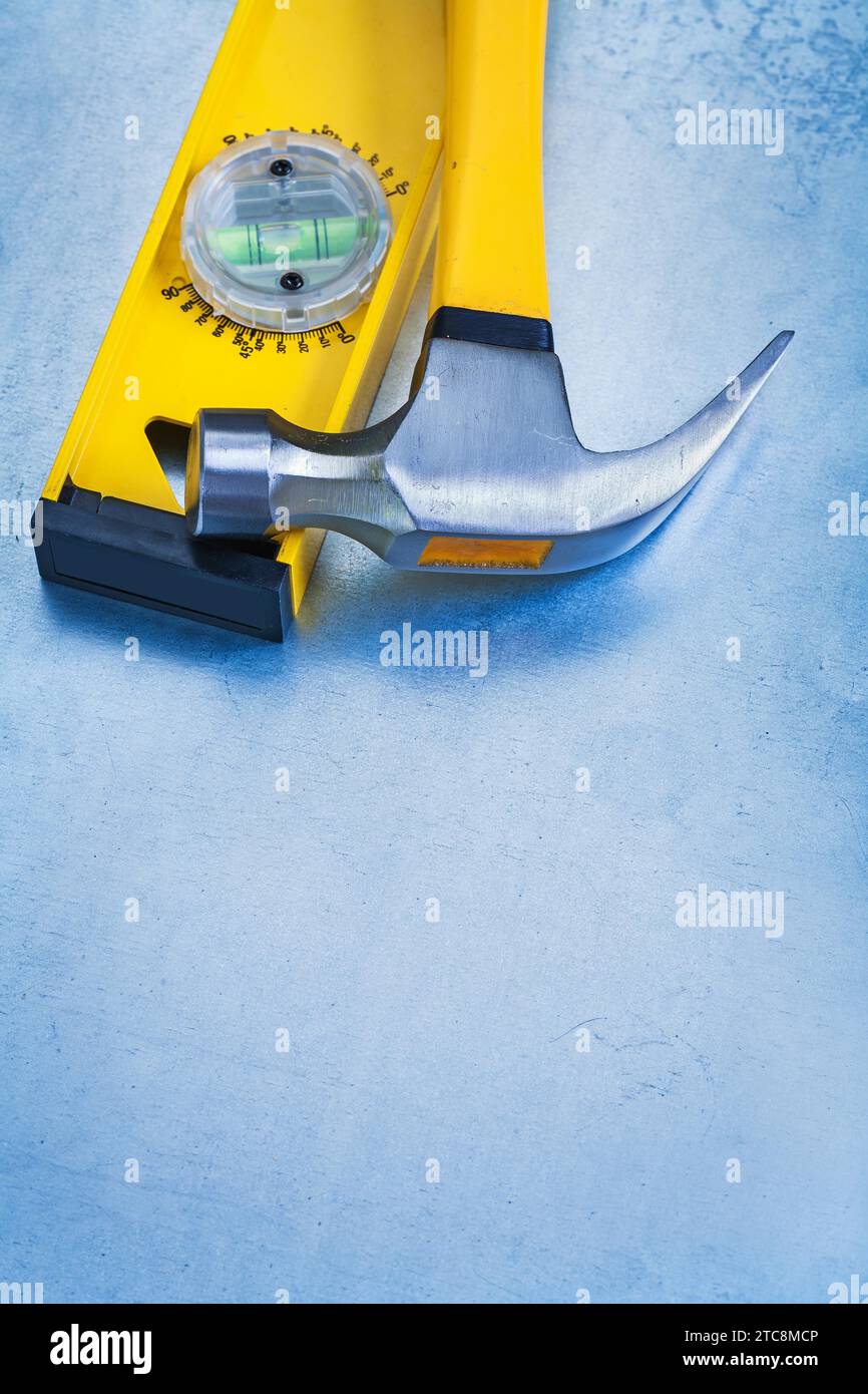 Vertical version of construction level and claw hammer on metallic ...