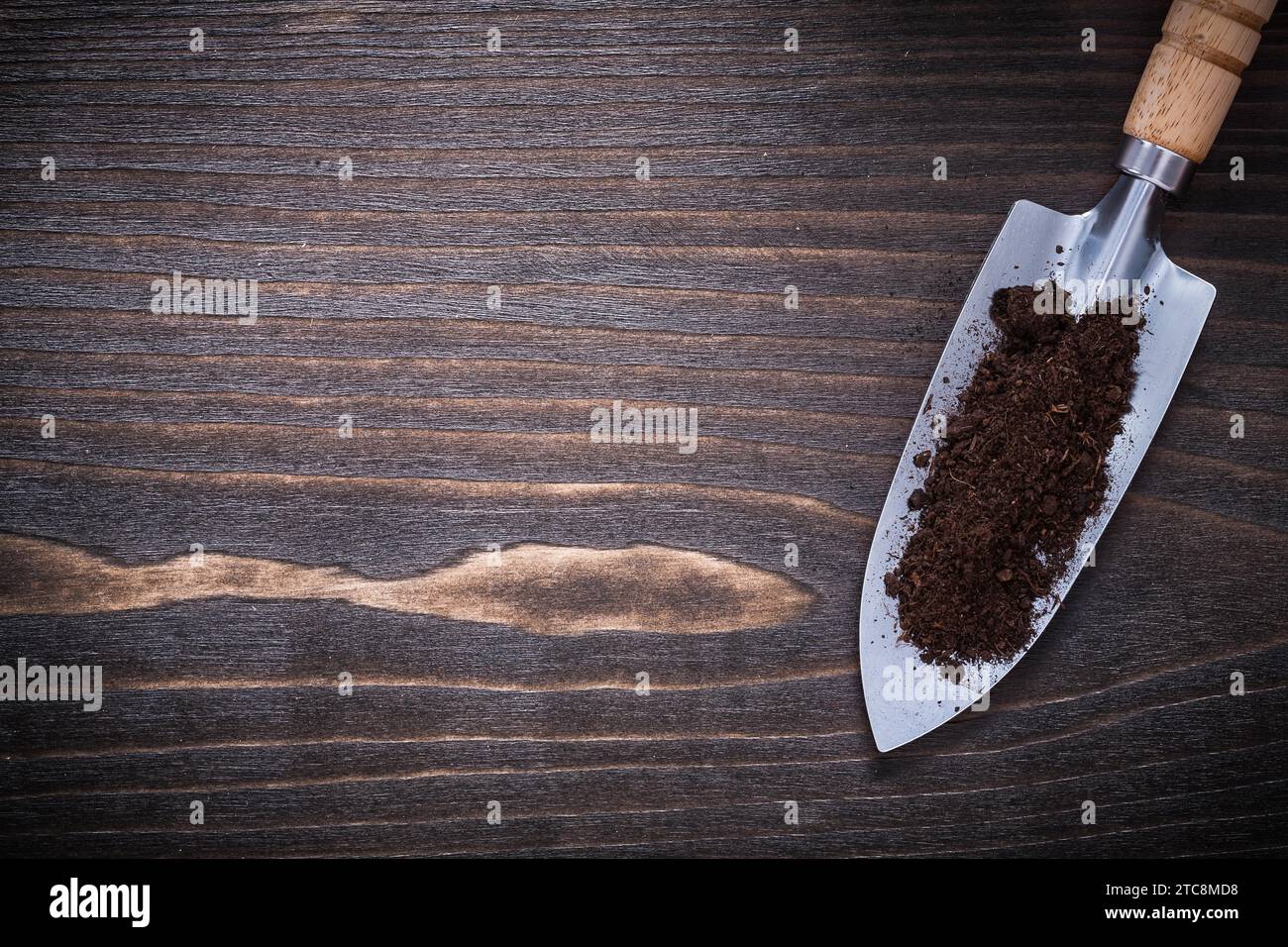 Stainless hand spade with soil on vintage wooden background copy space ...