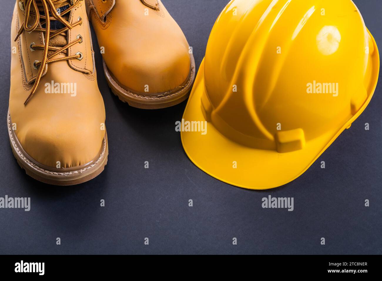 Working boots and helmet on black background Stock Photo - Alamy