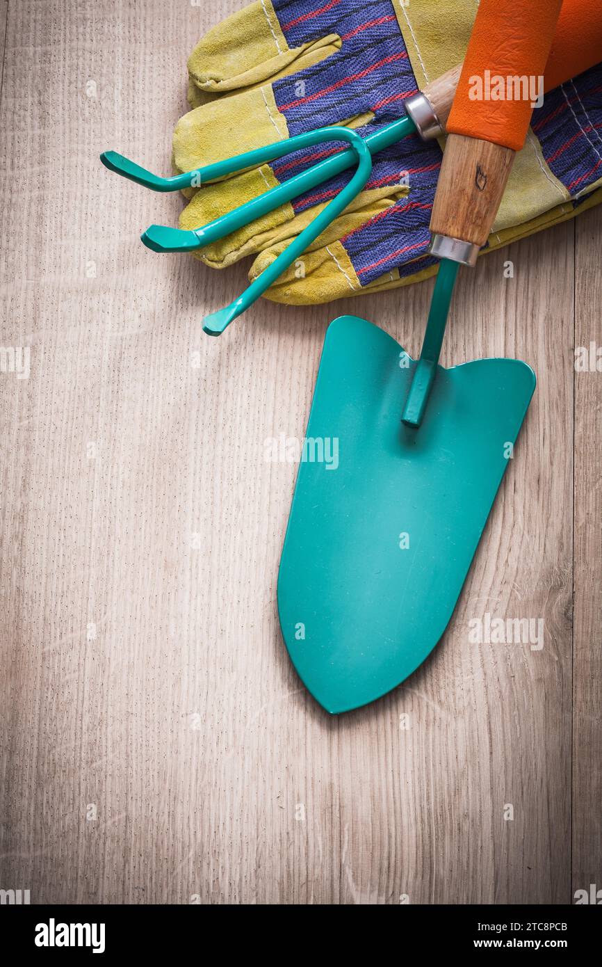 Gardening hand spade with metal rake and safety gloves on wooden ...