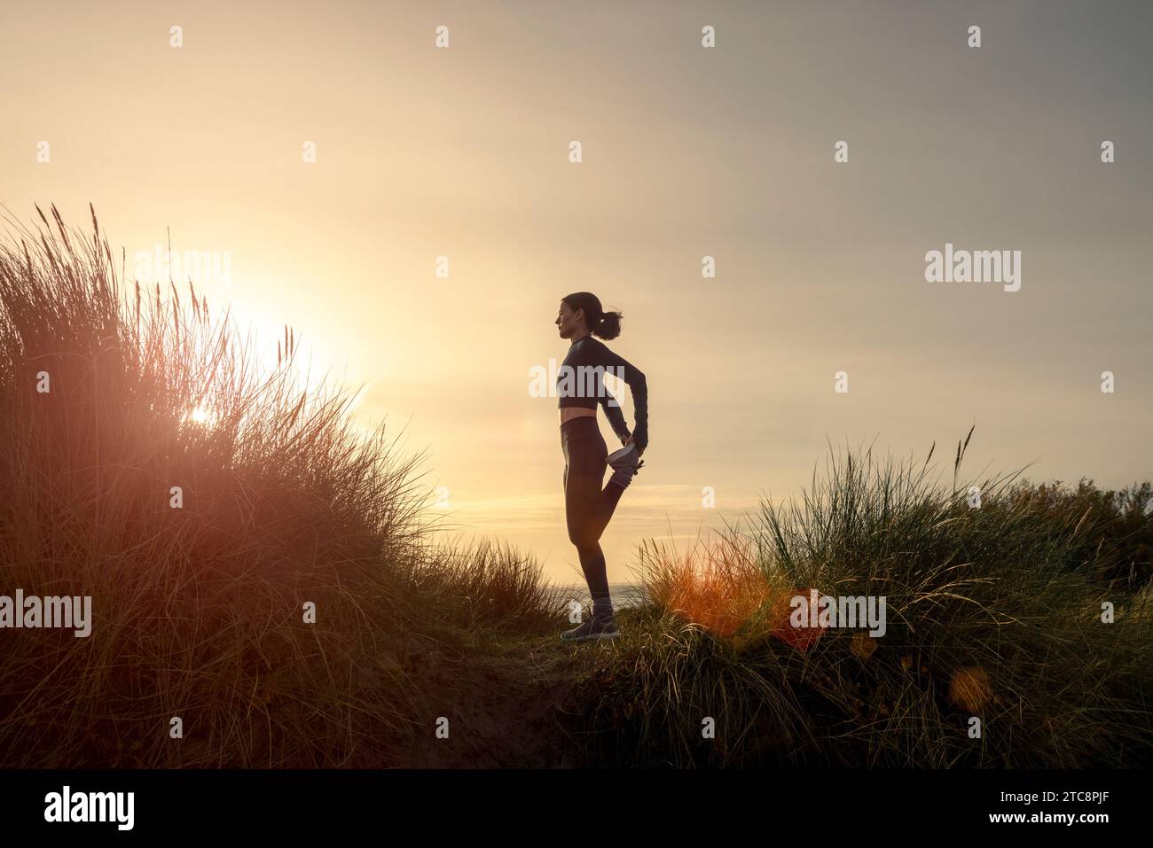 Sporty woman stretching her legs, doing standing quadricep front thigh ...