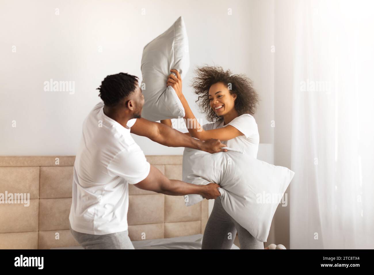 Joyful African Couple Having Pillow Fight For Fun In Bedroom Stock ...
