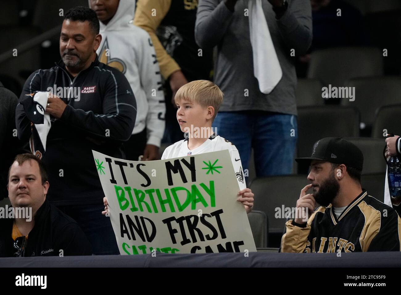 A New Orleans Saints fan holds a sign as he watches warm-ups before an ...