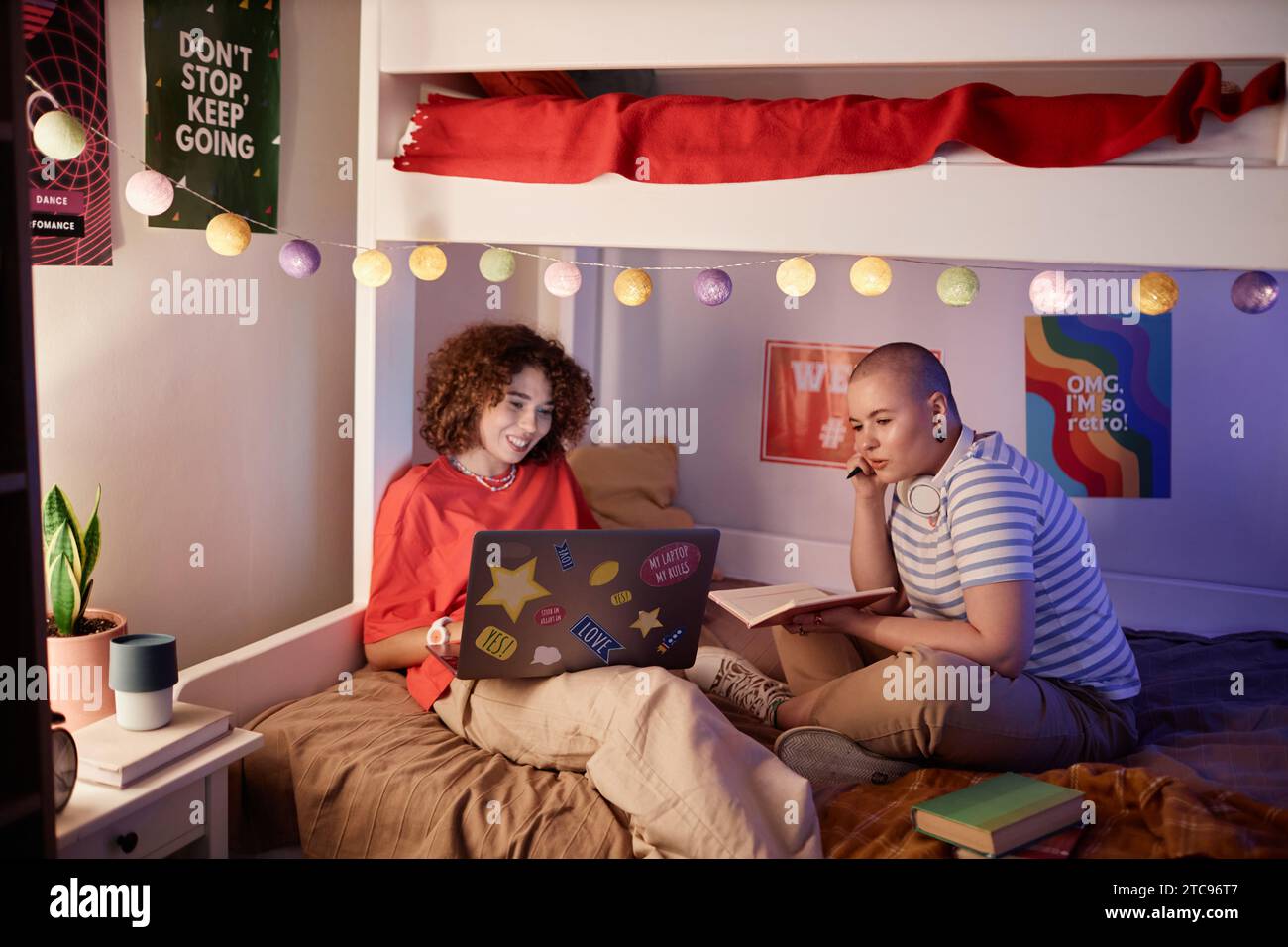 Portrait of two smiling young women sitting on bunk bed together and ...