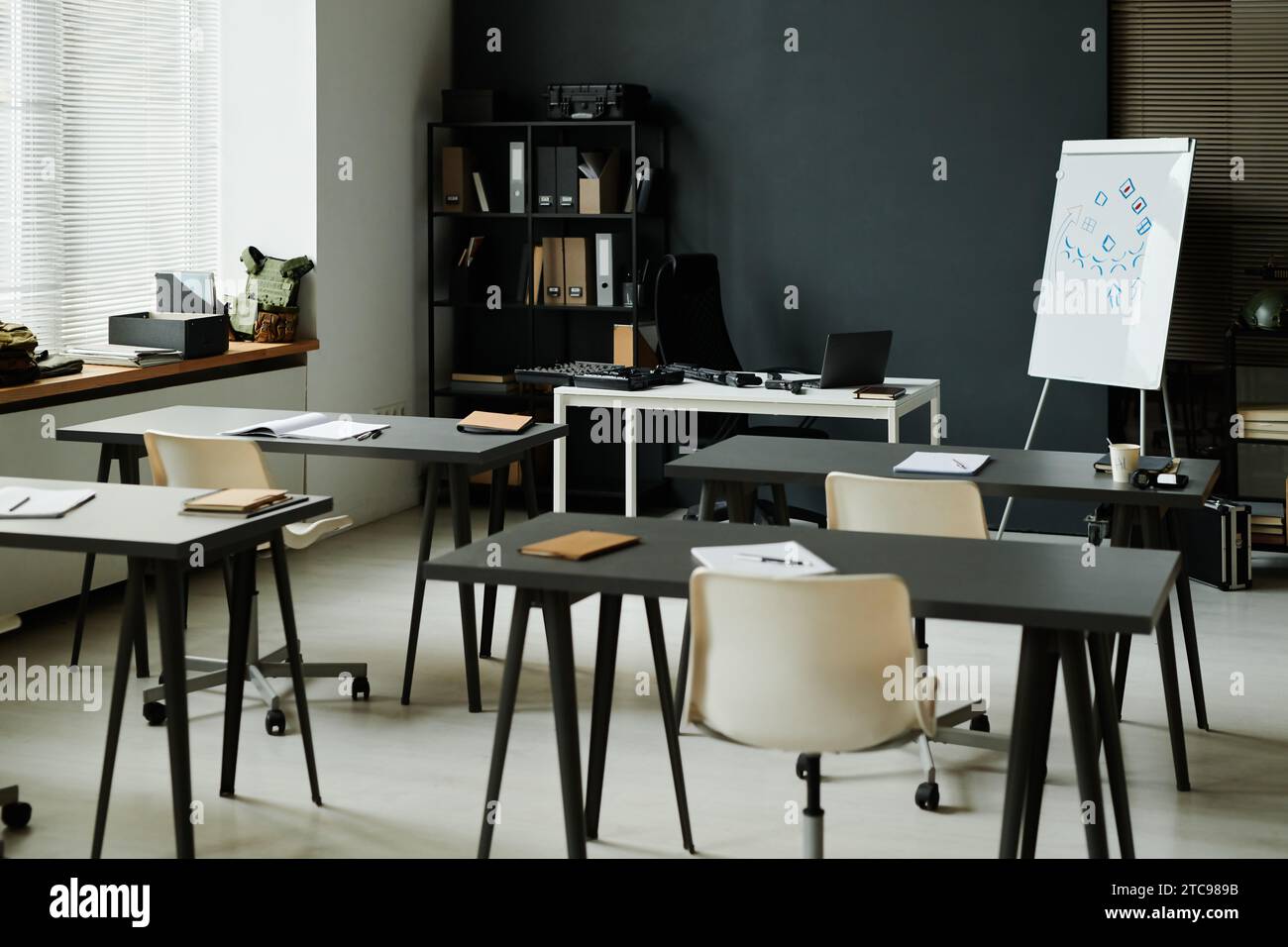 Part of spacious classroom with two rows of desks with chairs standing ...