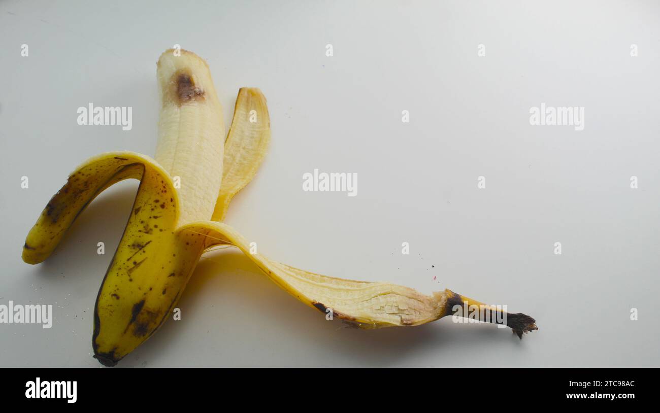 A close up photo of a ripe yellow banana with its skin peeled back on a ...
