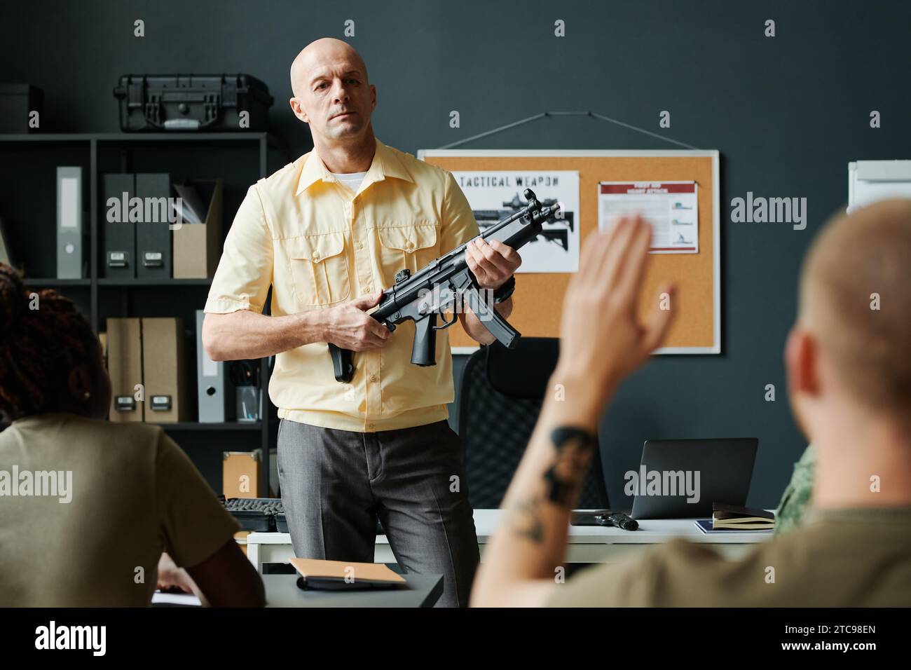 Serious male coach of military training with machine gun in hands ...