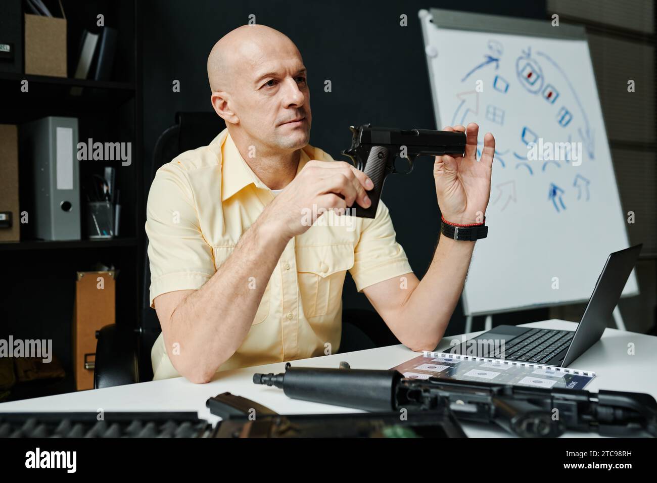 Bald mature male coach of military training sitting by workplace and ...
