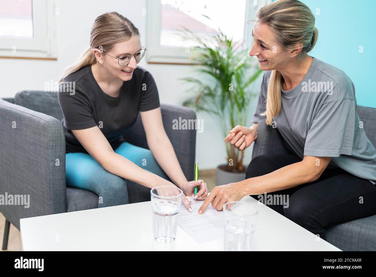 Two women smiling and engaging in conversation with one writing on a ...