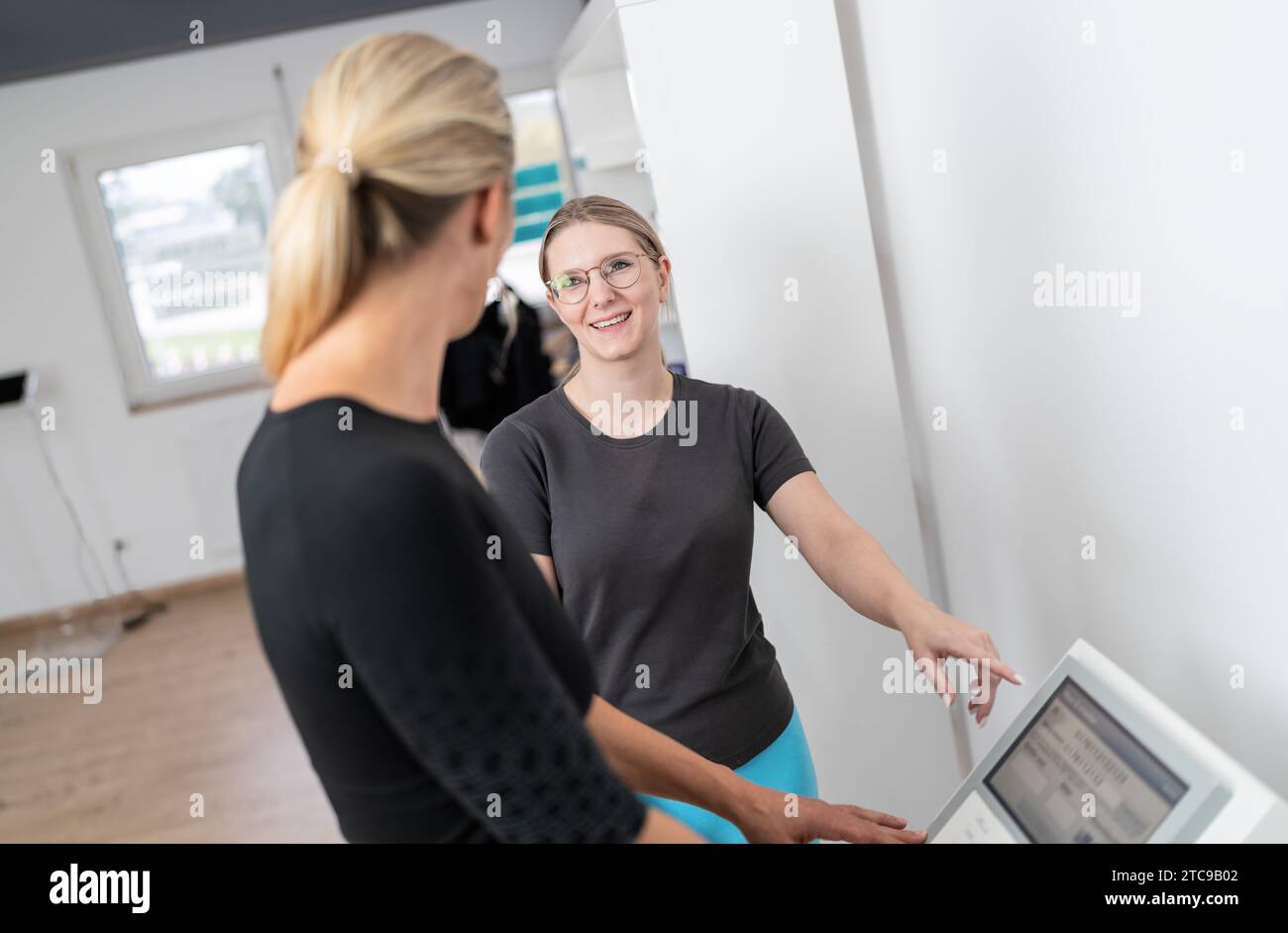 Female trainer pointing at a body composition scale’s display to ...