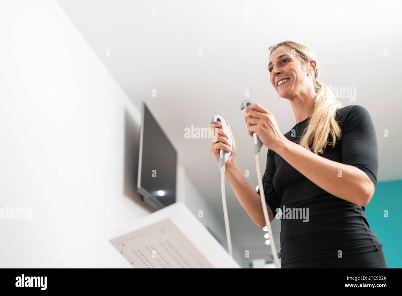 Client smiling holding grips of a body composition measuring scale for ...