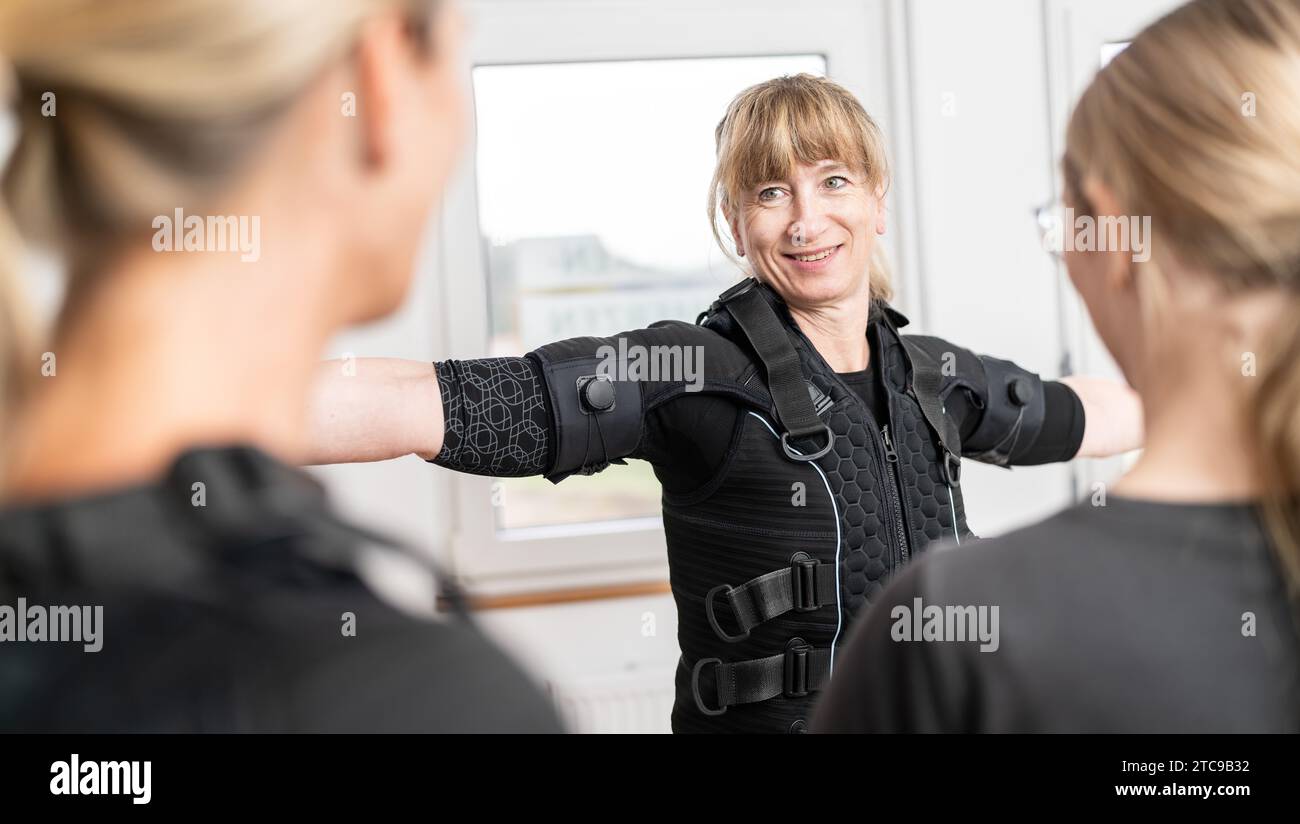woman is being assisted with fitting an EMS training suit by a trainer ...